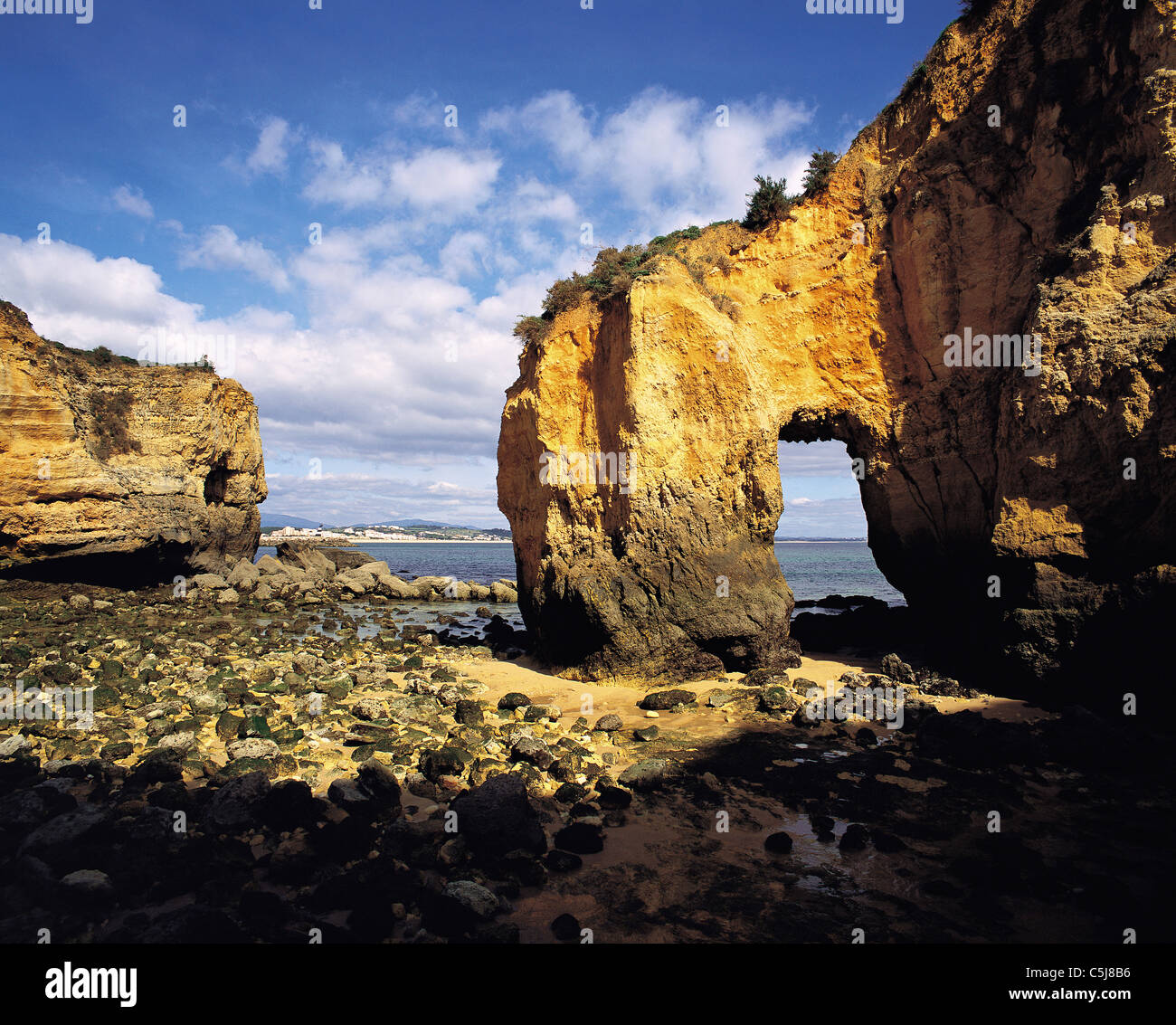 Rock formations including a natural arch along the shore at Lagos ...