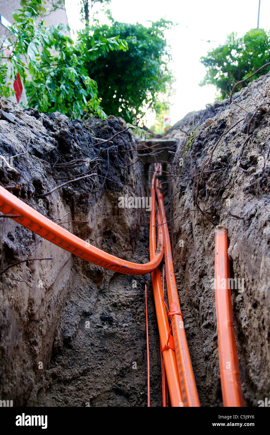 Orange fiberglass cables in a trench in a Dutch city, connecting ...