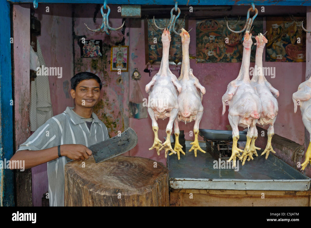 Young indian butcher at Mysore market proudly posing with his meat axe ...