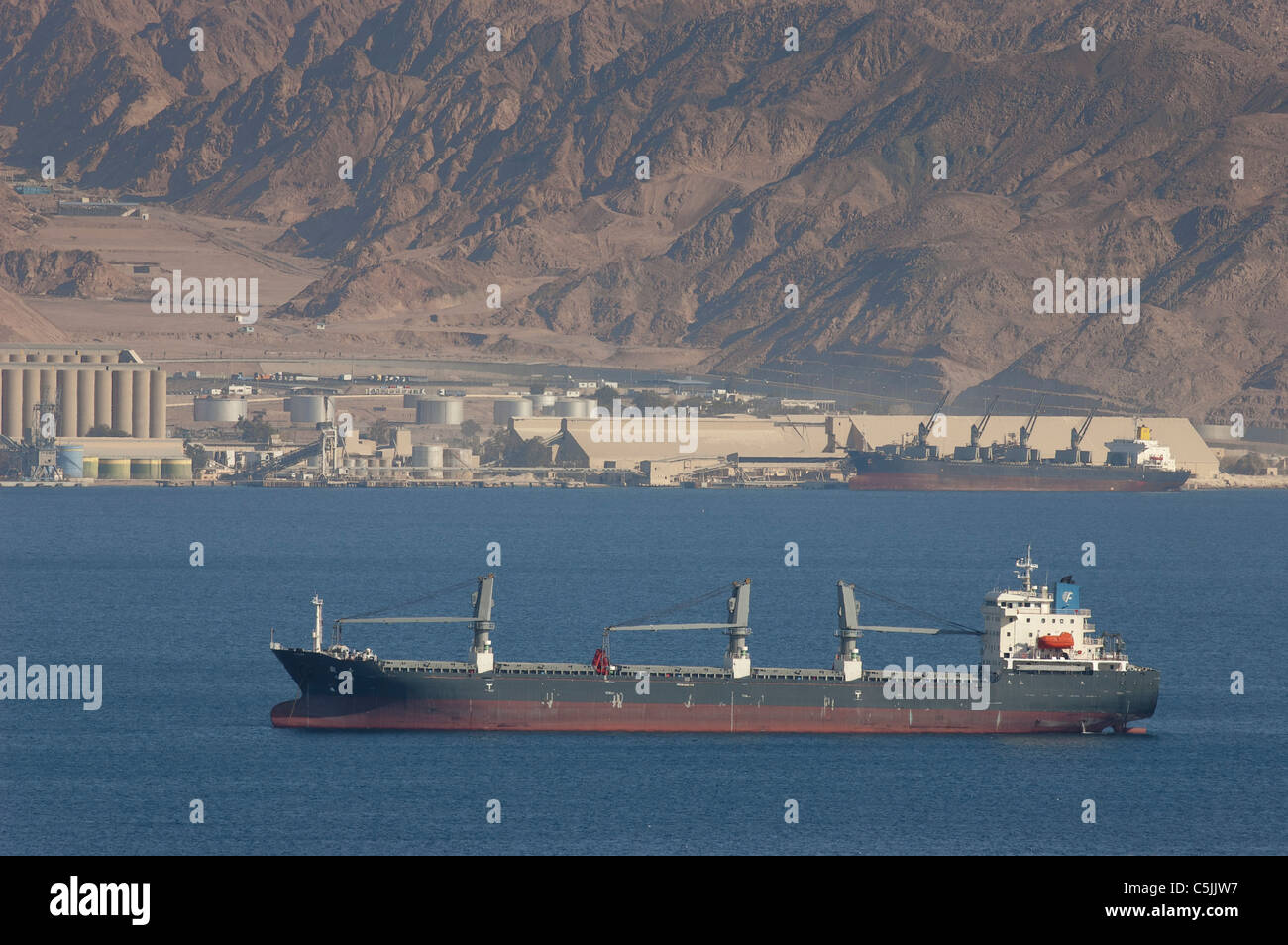 An anchored dry bulk freighter in ballast. In the background: Arab ...