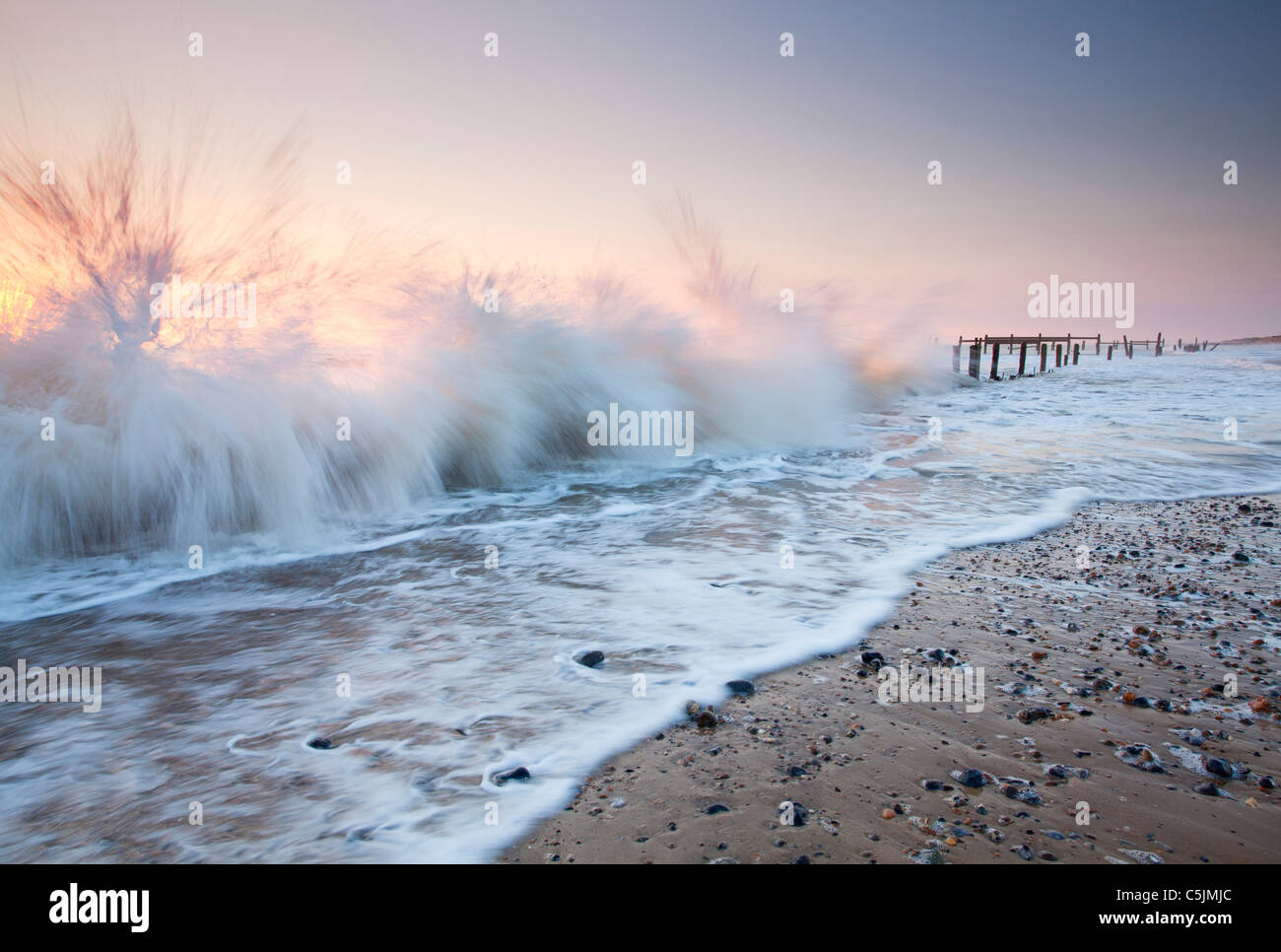 Powerful waves crash against the derelict wooden and metal sea defences ...