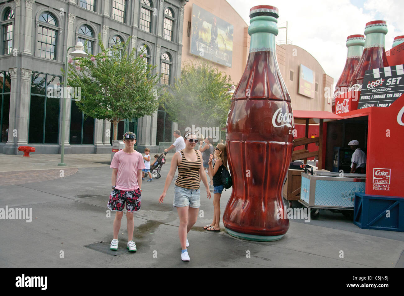 teenage kids cooling down witha mist spray large coke bottle in ...