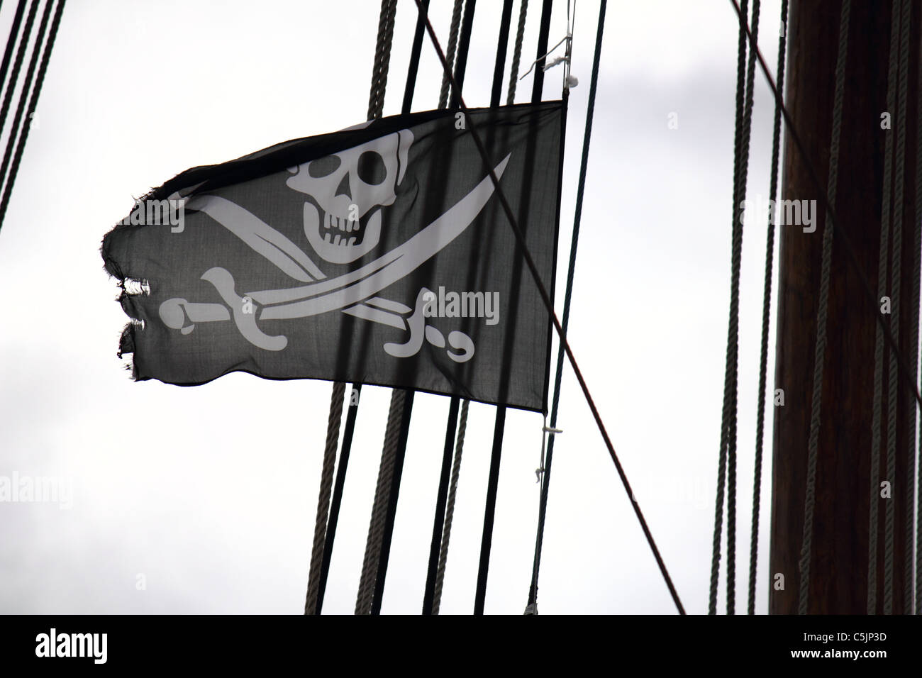 a ragged black and white pirate flag in the mast of a sailboat catching ...