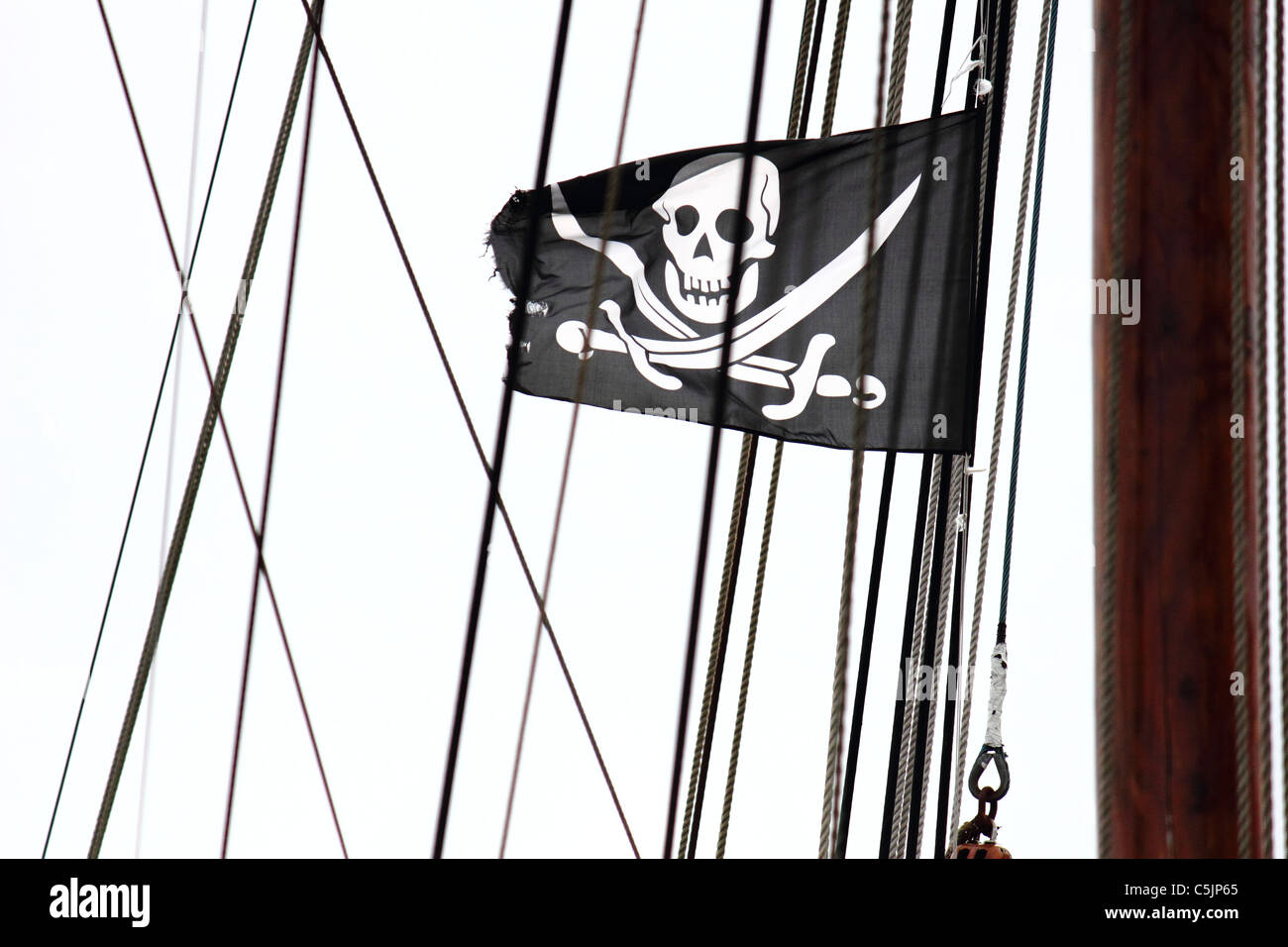 a ragged black and white pirate flag in the mast of a sailboat catching ...