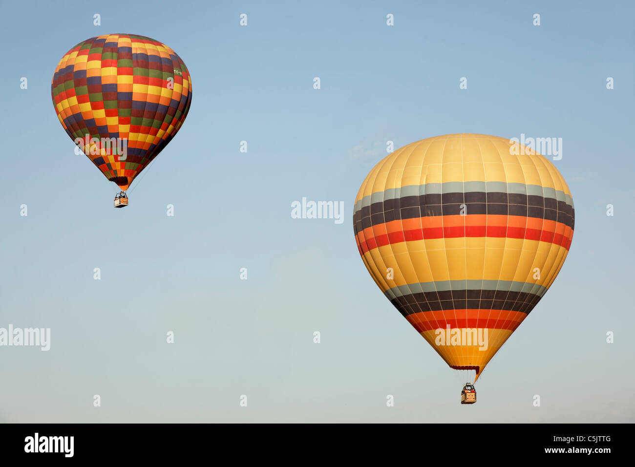 two colorful hot air balloons high in a light blue sky, horizontal ...