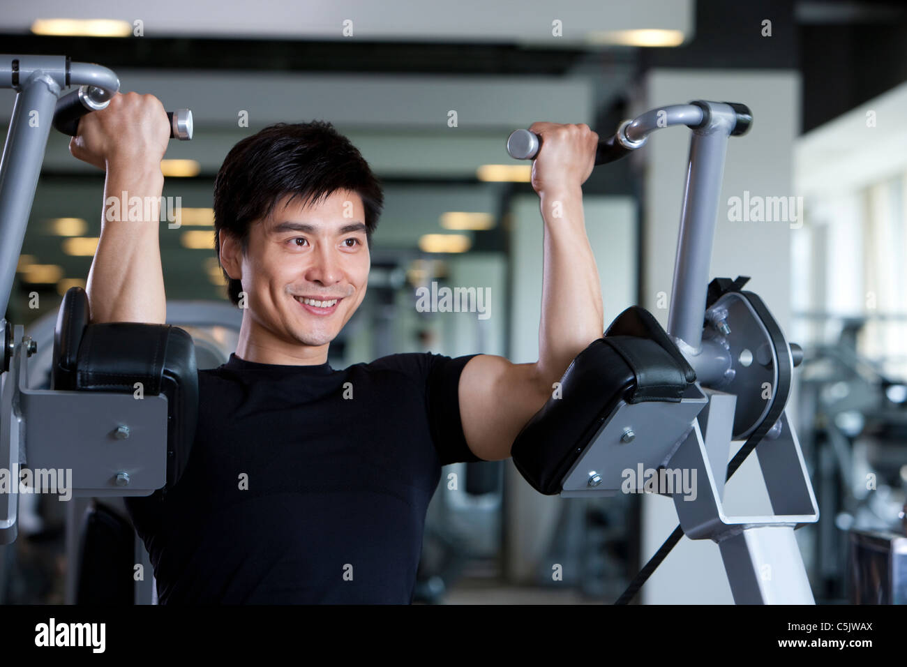 Young Man Using Exercise Machine Stock Photo - Alamy