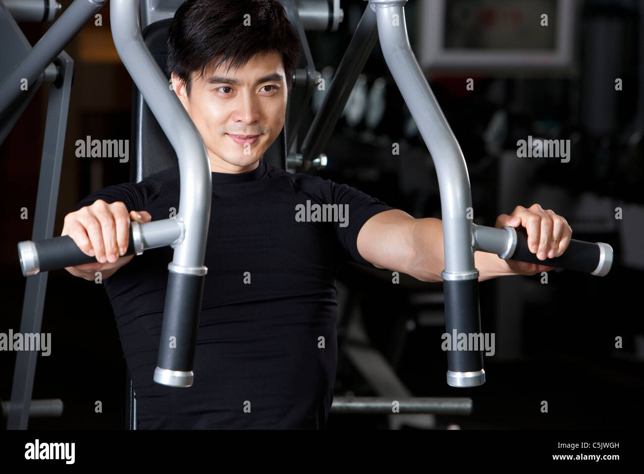Young Man Using Exercise Machine Stock Photo - Alamy
