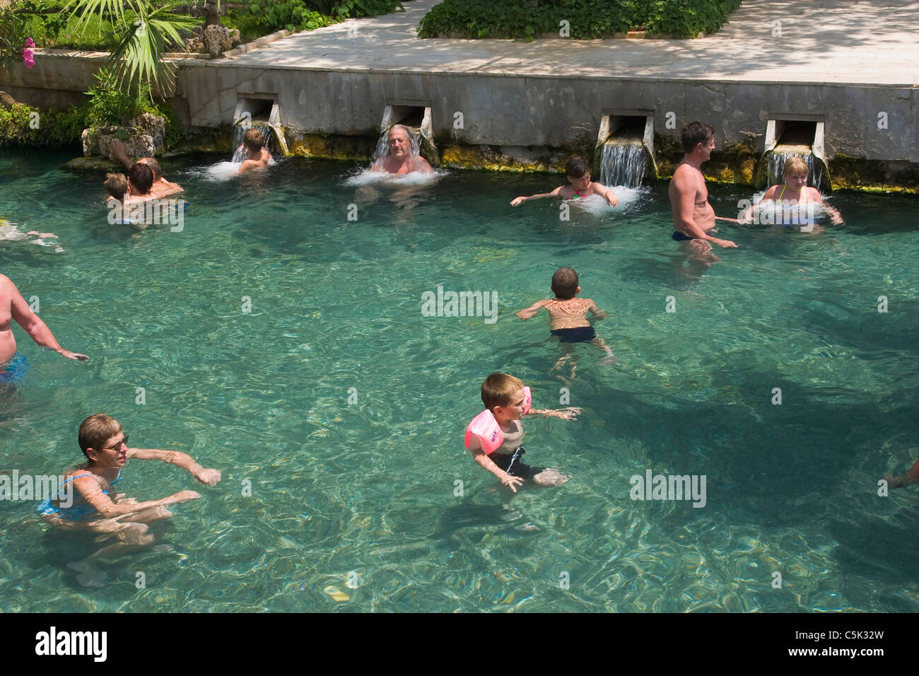 Tourists bathing and swimming in the ancient Sacred Pool of Hierapolis ...