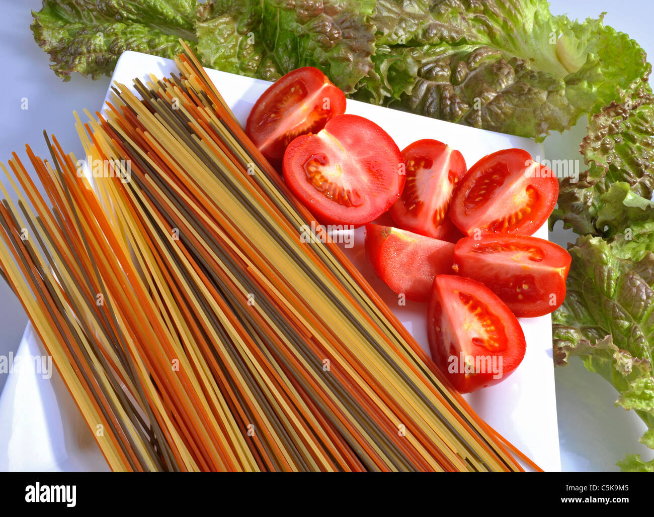 Coloured spaghetti with tomatoes Stock Photo - Alamy