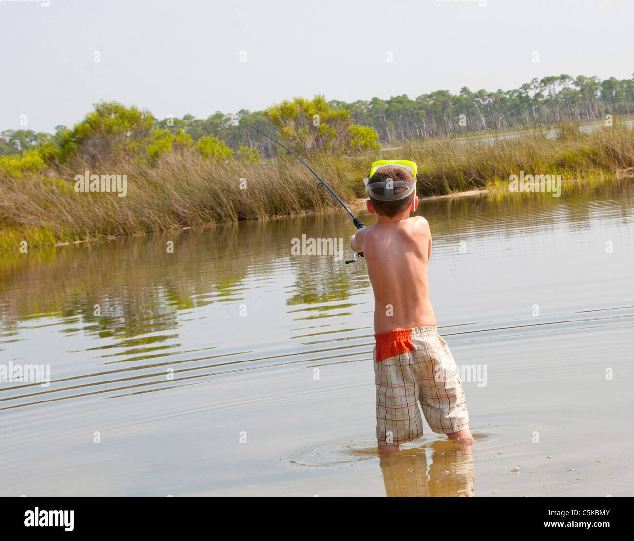 Young boy wading in water while casting Stock Photo - Alamy
