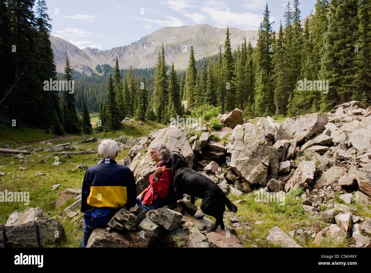 Hikers rest in alpine setting with dog Stock Photo - Alamy