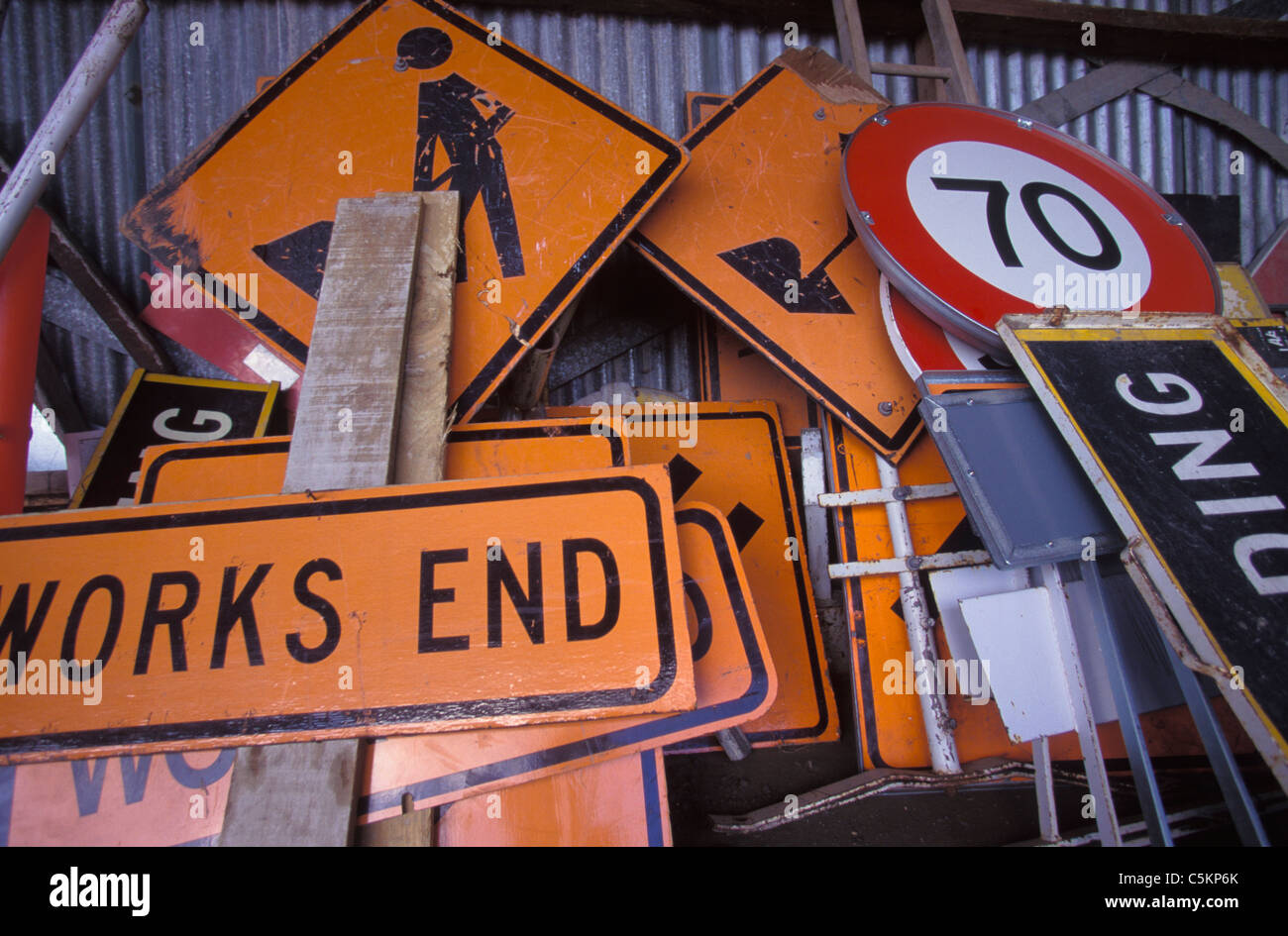 Roadsigns stacked up against in a corrugated iron wall in a warehouse ...