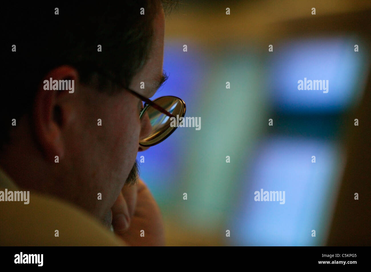 Computer room, man looking at screen refracting through his glasses ...