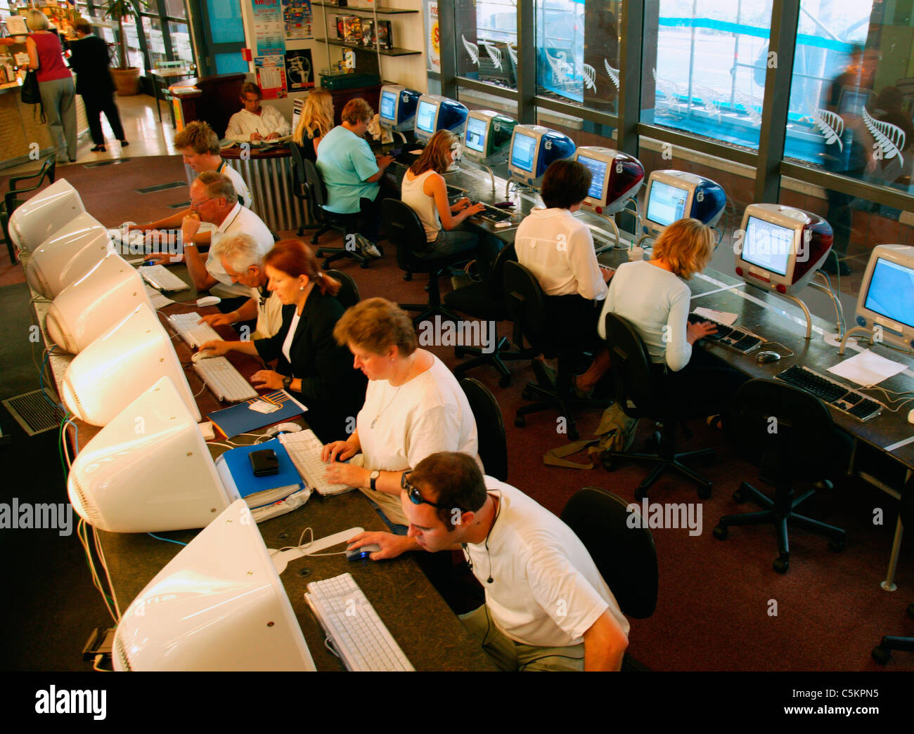 Two rows of people sitting at computers in an internet cafe, emailing ...