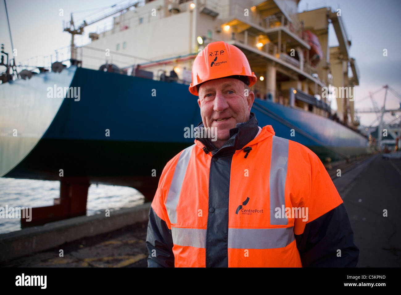 Man, port worker, standing smiling at camera, wearing high-visibility ...