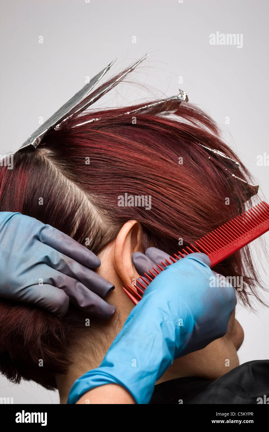 Hair colorist applying color to clients hair Stock Photo - Alamy