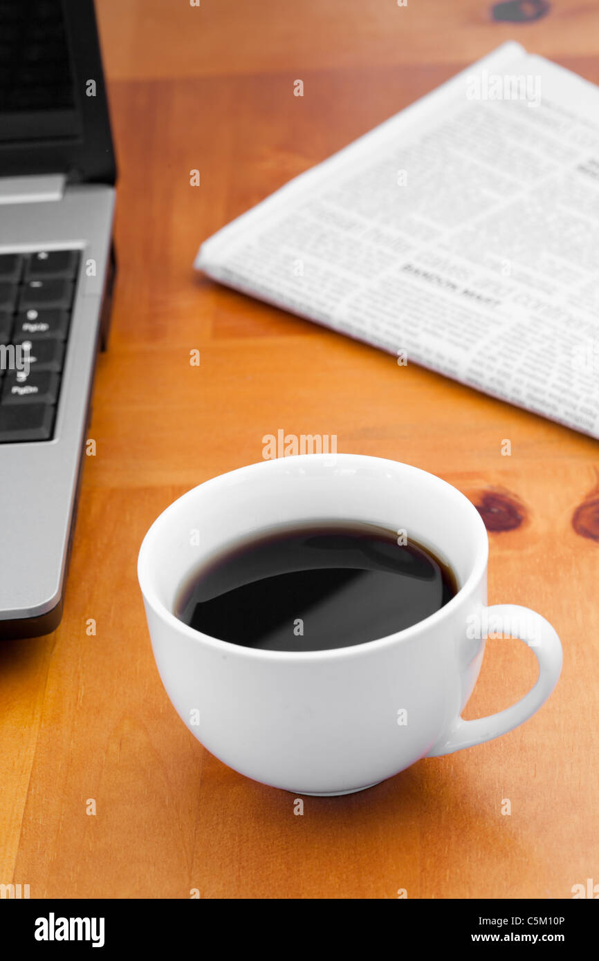 A cup of coffee with a laptop and a newspaper Stock Photo - Alamy