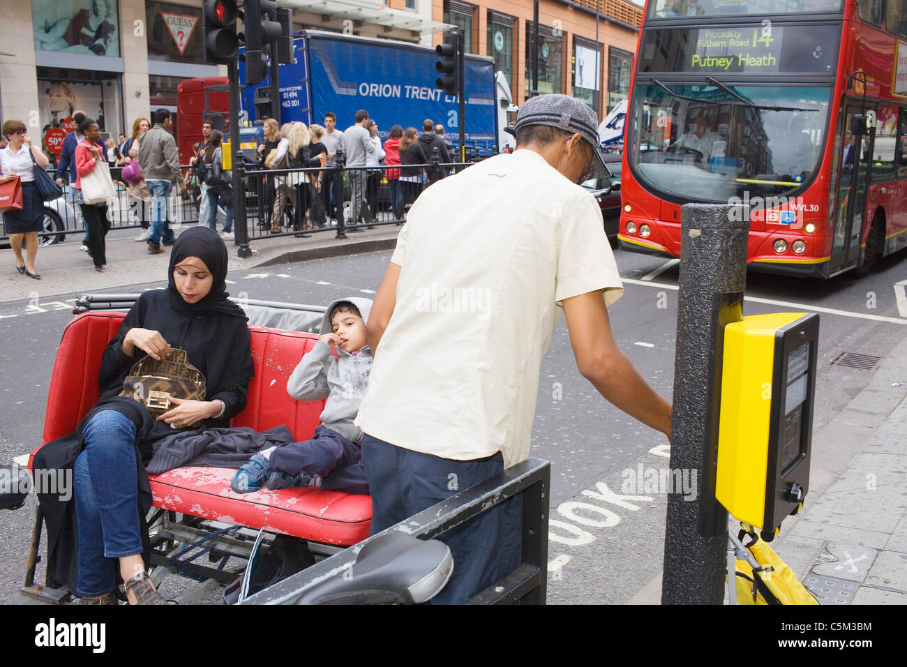 A Muslim woman with a young boy in the back of a Rickshaw on the street ...