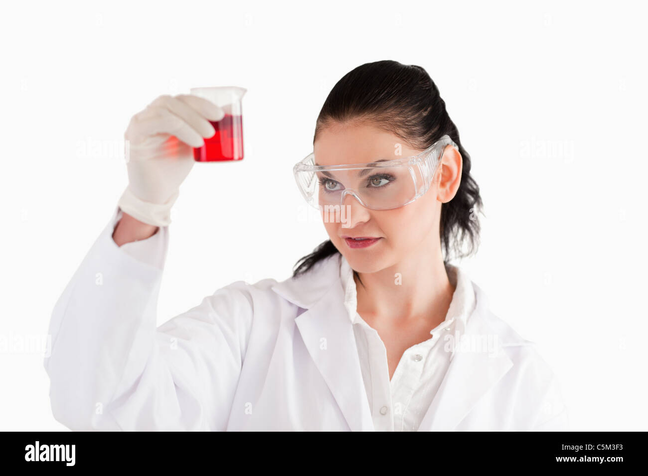 Dark-haired woman looking at a red beaker Stock Photo - Alamy