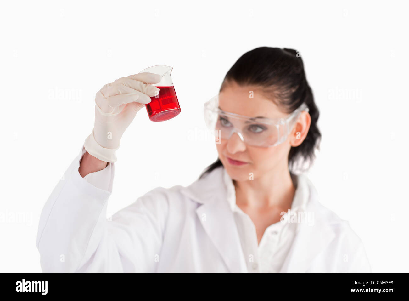 Scientist looking at a red beaker Stock Photo - Alamy