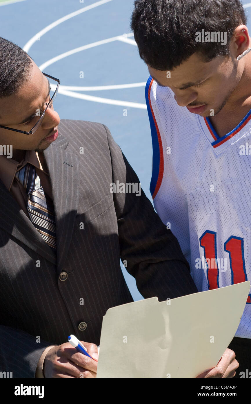 A basketball player being coached or recruited by a college recruiter ...