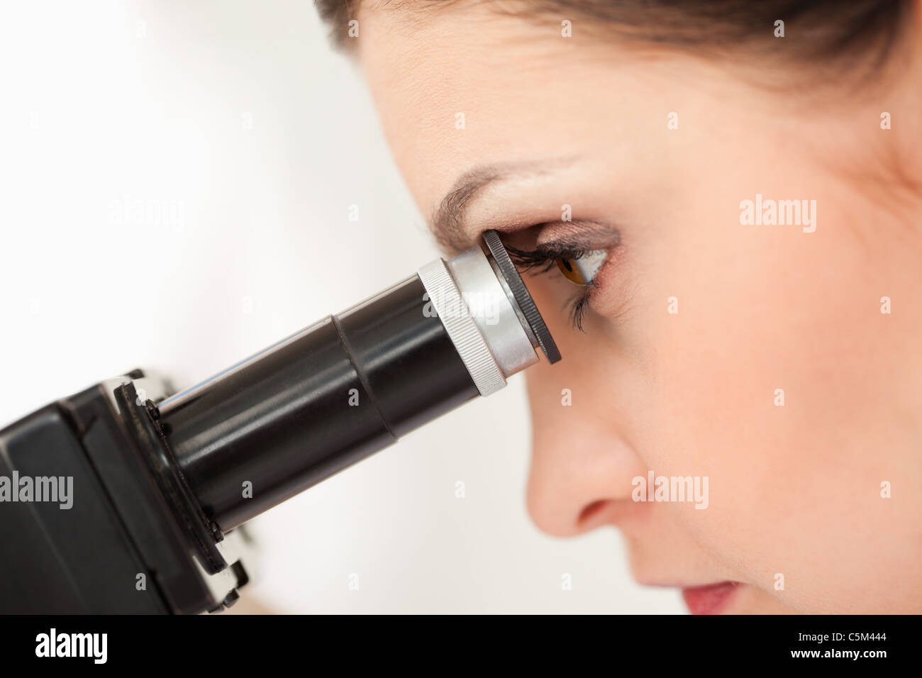 Dark-haired scientist looking through a microscope Stock Photo - Alamy