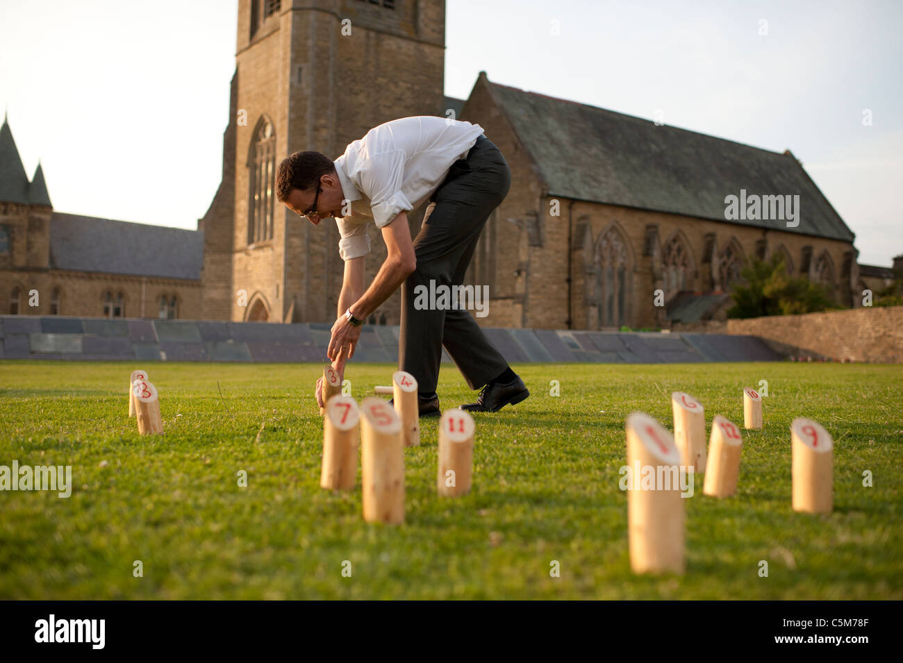 a man setting up a home-made version of the Finnish game "Molkky Stock ...