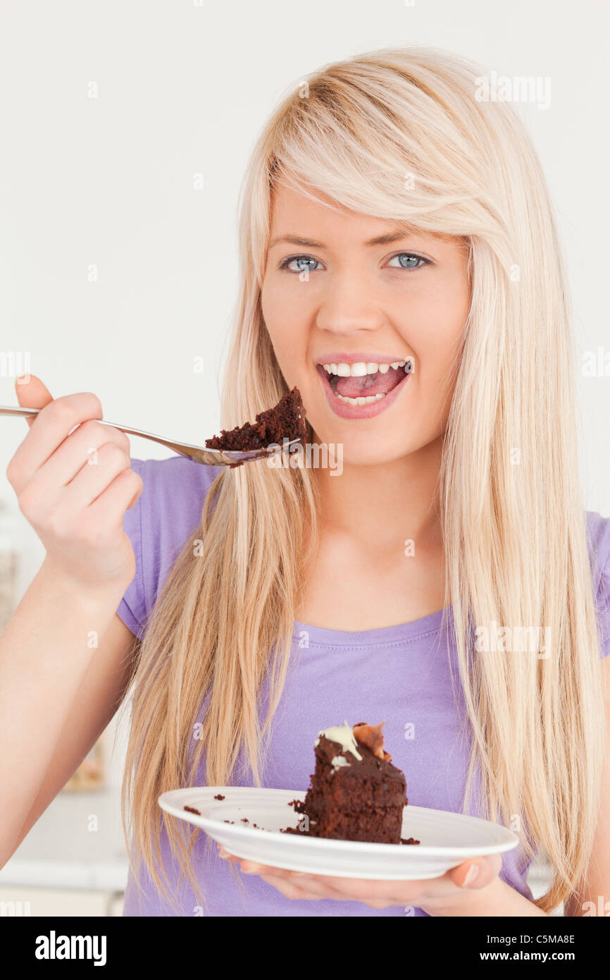 Smiling blonde female eating cake Stock Photo - Alamy