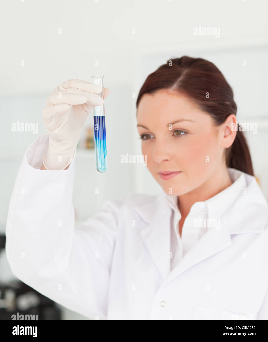 Beautiful red-haired scientist looking at the camera while holding a ...