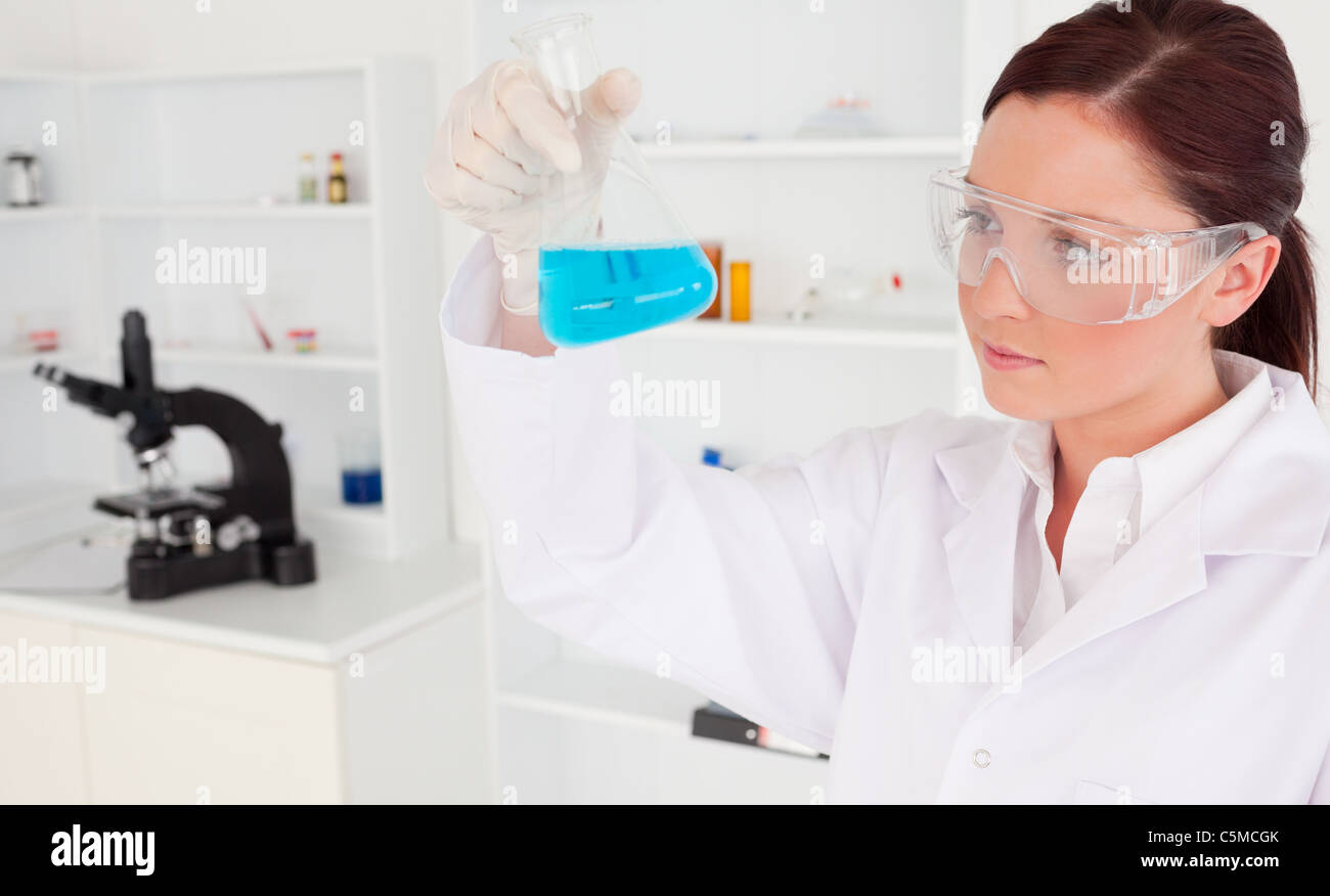 Cute female scientist looking at a beaker in a lab Stock Photo - Alamy