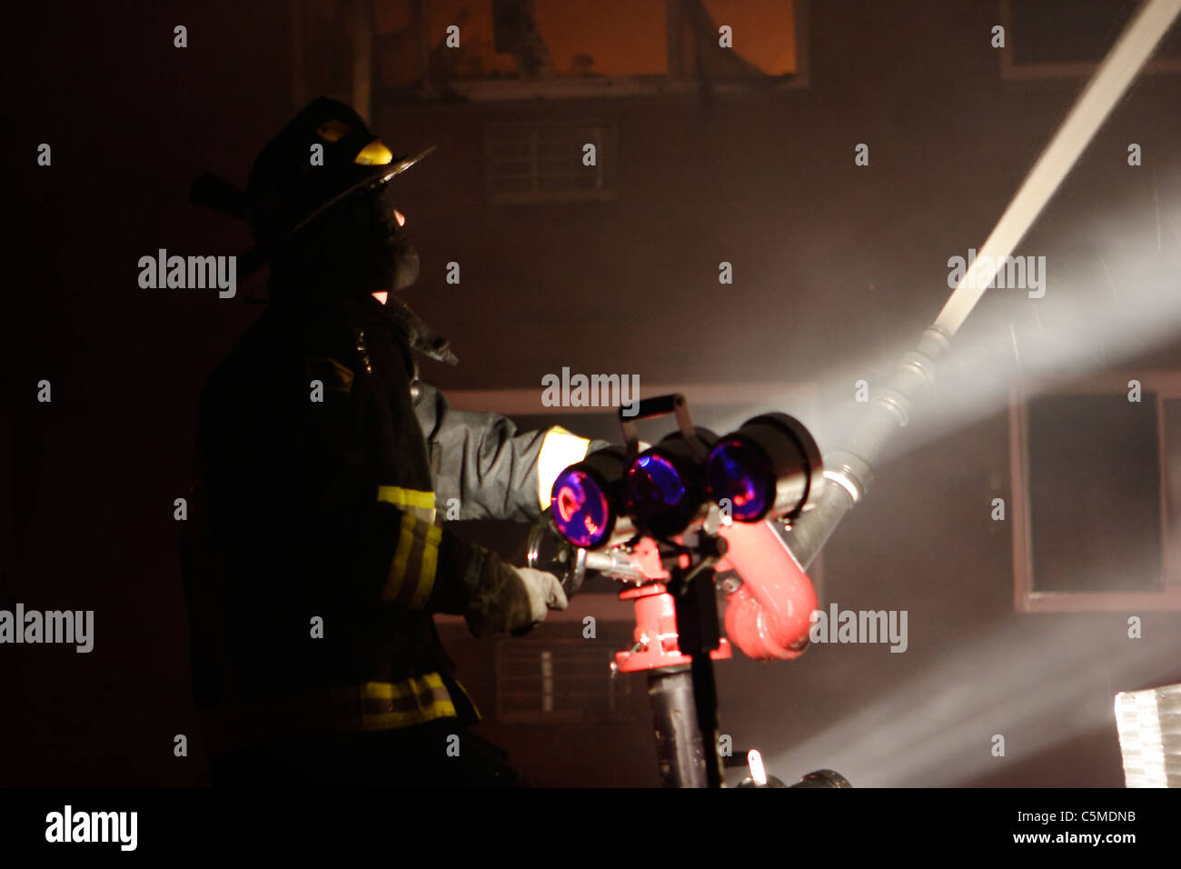 Silhouette of an American Firefighter using a deck gun at night Stock ...