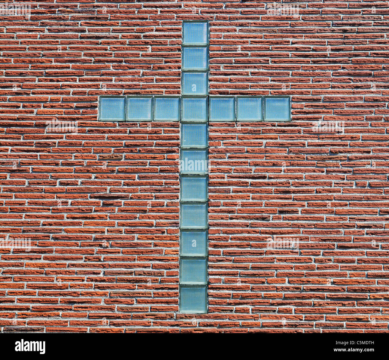 Blue glass brick or block cross on a thin red brick wall of a church ...