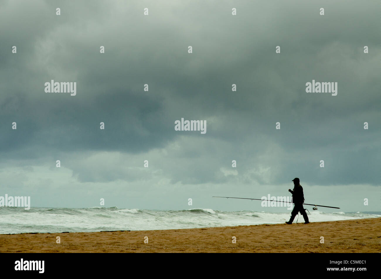 Angler walking by the beach in cloudy day Stock Photo - Alamy