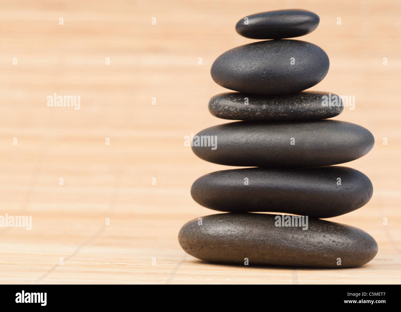Black stones stack against bamboo background Stock Photo - Alamy
