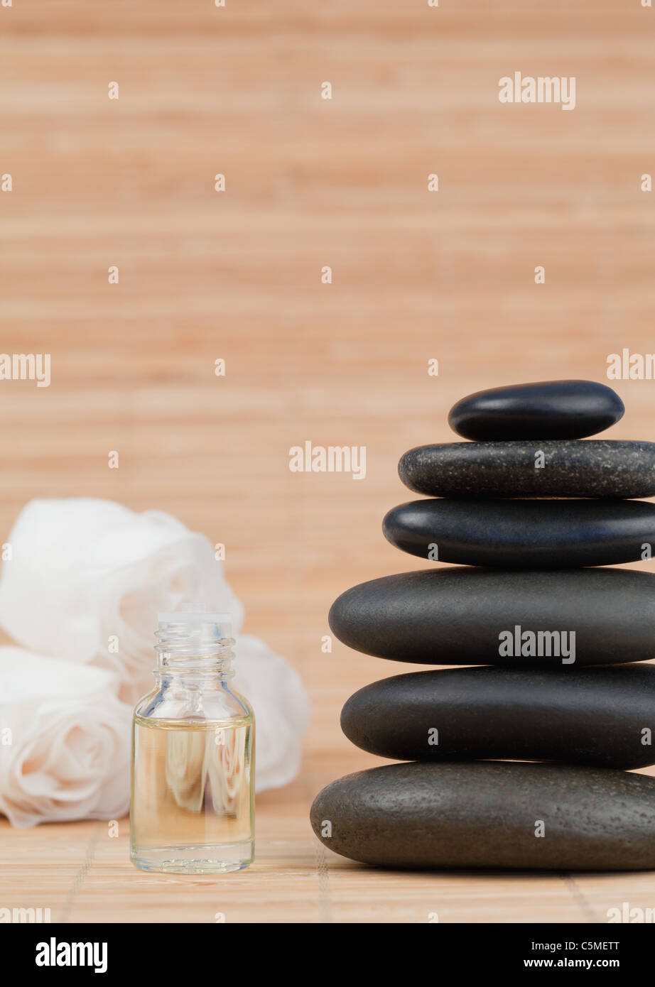 Glass phial with roses and a stack of black pebbles Stock Photo - Alamy