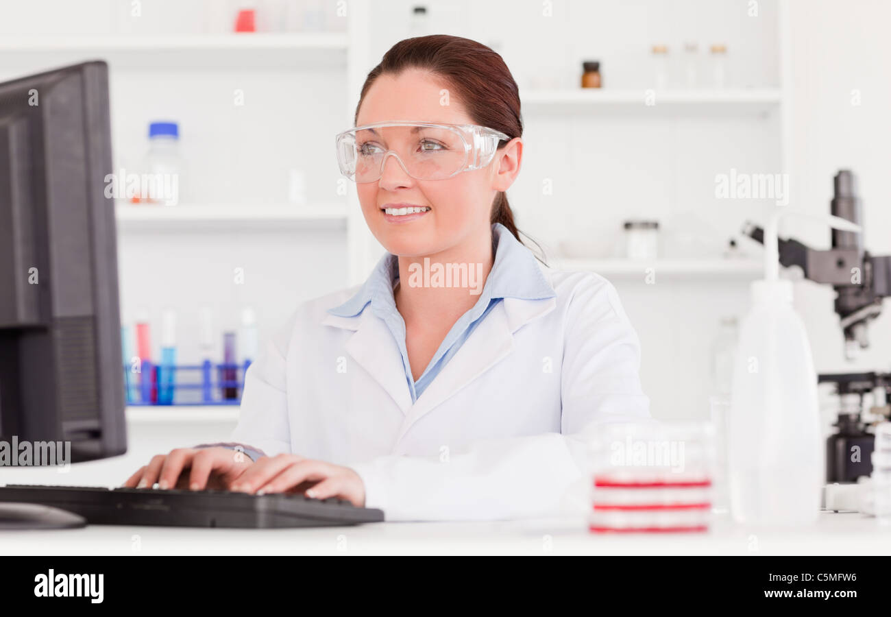 Cute scientist typing a report with her computer Stock Photo - Alamy