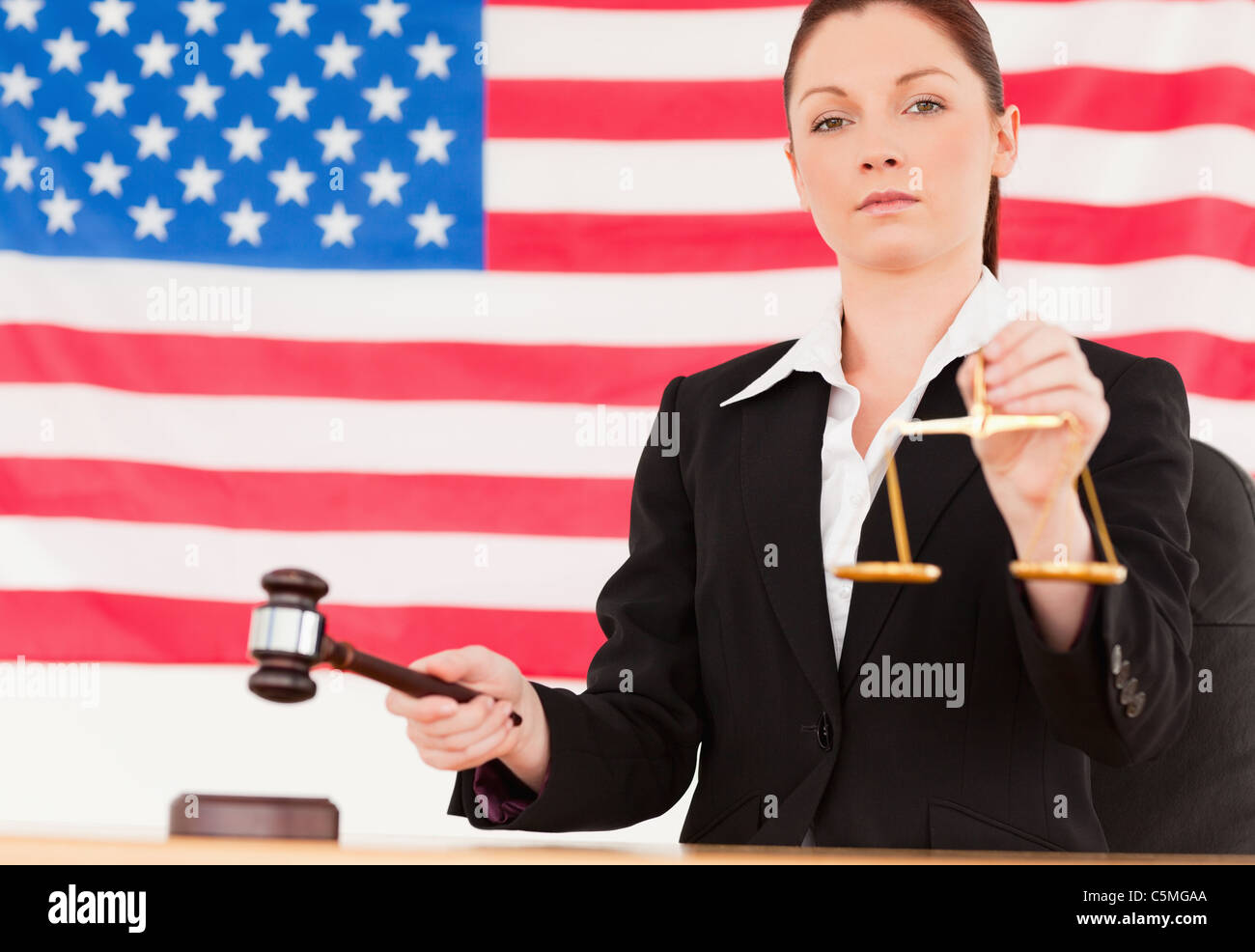 Close up of a cute judge knocking a gavel and holding scales of justice ...
