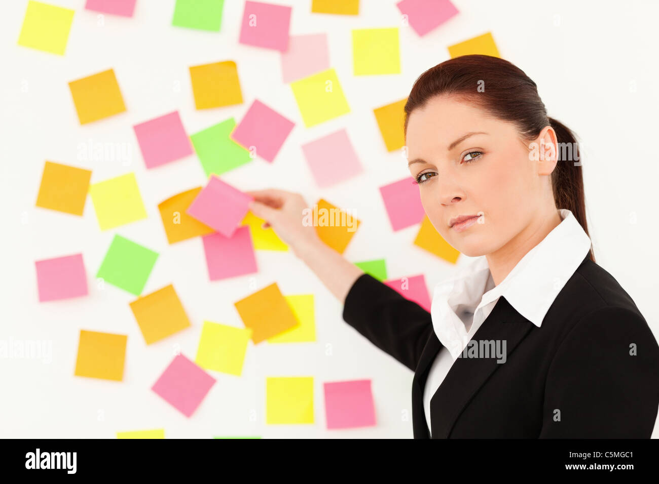 Serious woman putting repositionable notes on a white wall Stock Photo ...