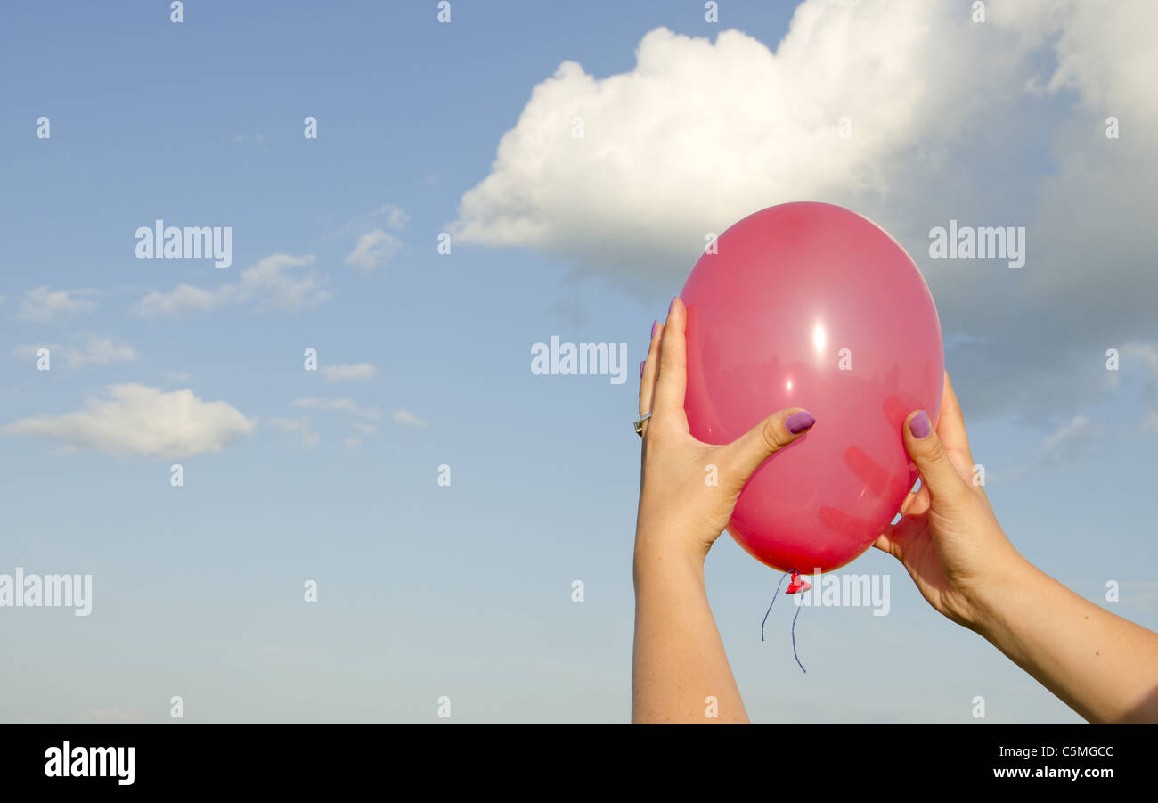 womans hand holding red balloon on sky background Stock Photo - Alamy