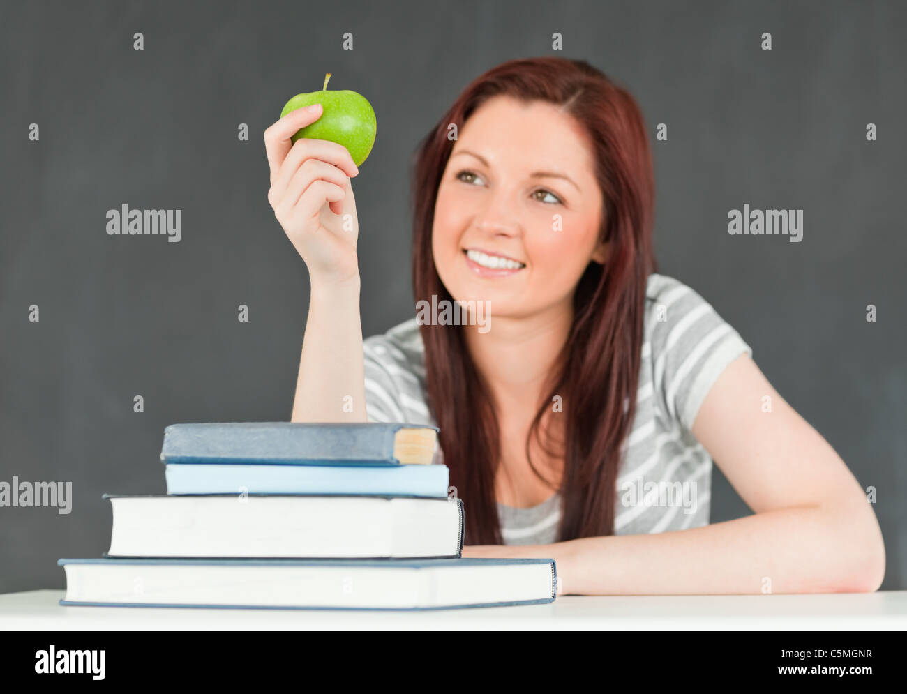 Young student in a classroom looking at an apple Stock Photo - Alamy