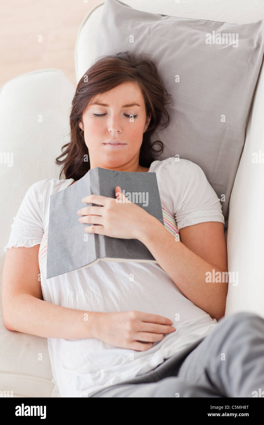 Young beautiful female having a rest and reading a book while lying on ...
