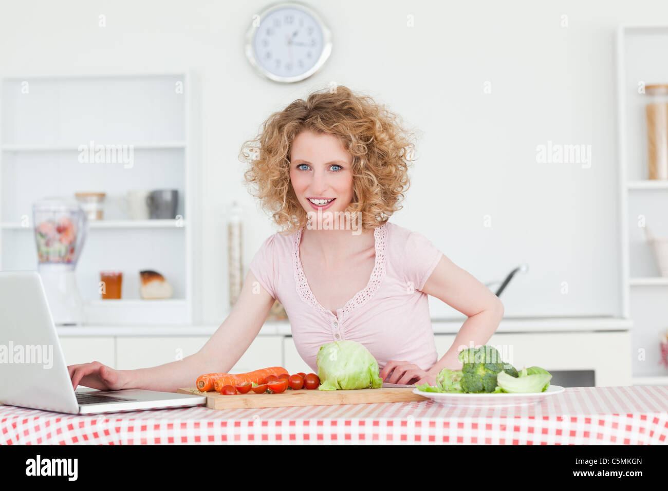 Beautiful blonde woman relaxing with her laptop while cooking Stock ...