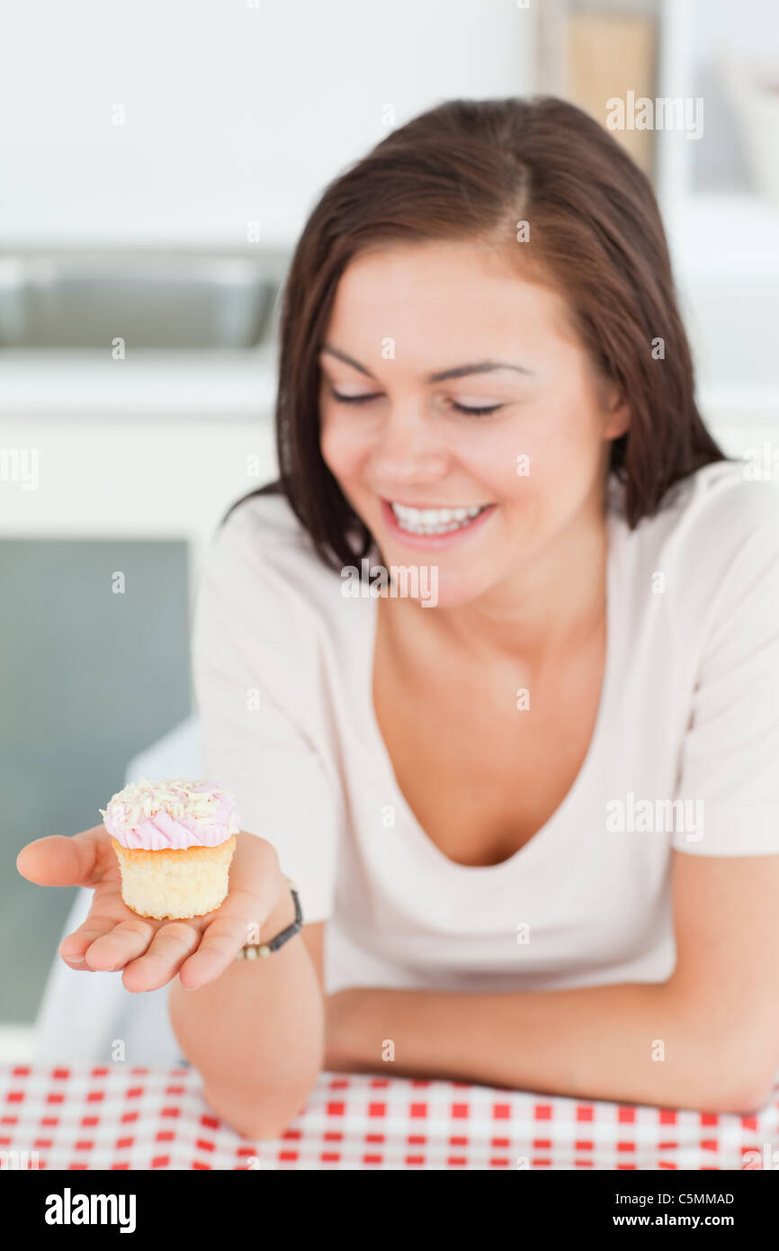Laughing brunette looking at a cupcake Stock Photo - Alamy