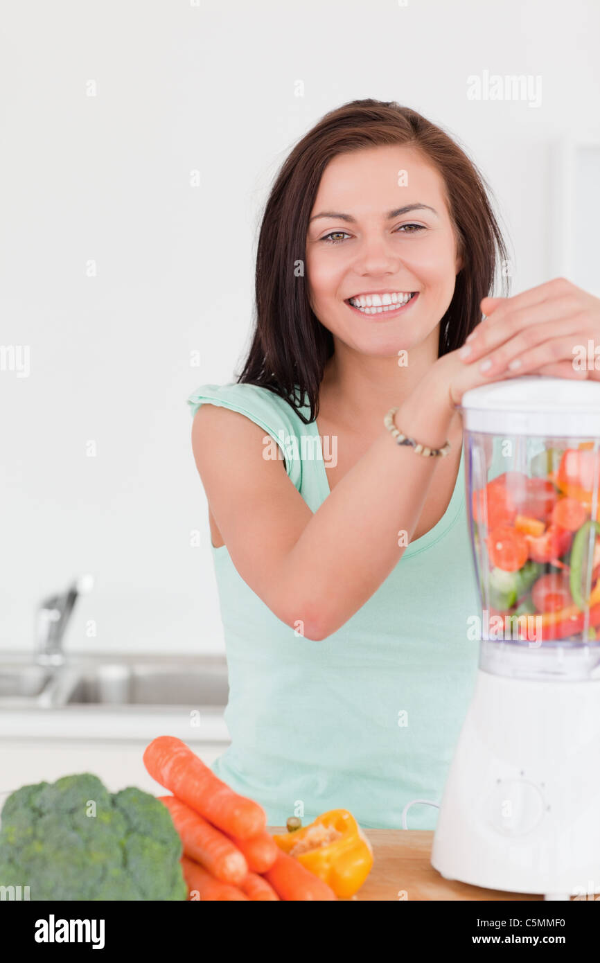 Charming dark haired woman posing with a blender Stock Photo - Alamy