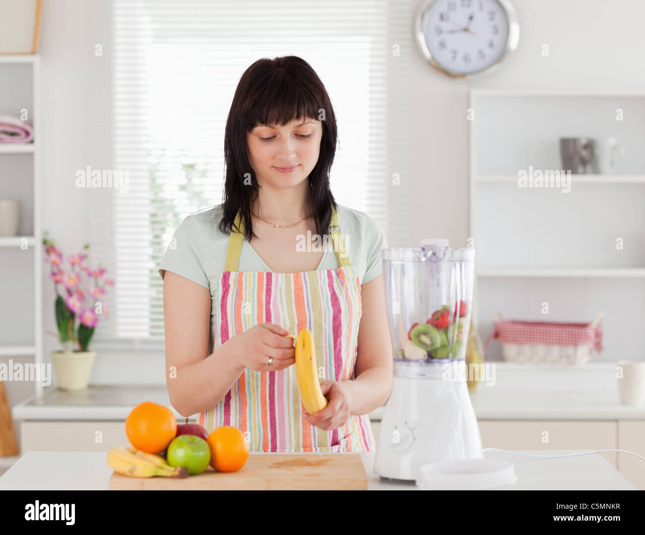 Good looking brunette woman pealing a banana while standing Stock Photo ... Good looking brunette woman pealing a banana while standing Stock Photo ...
