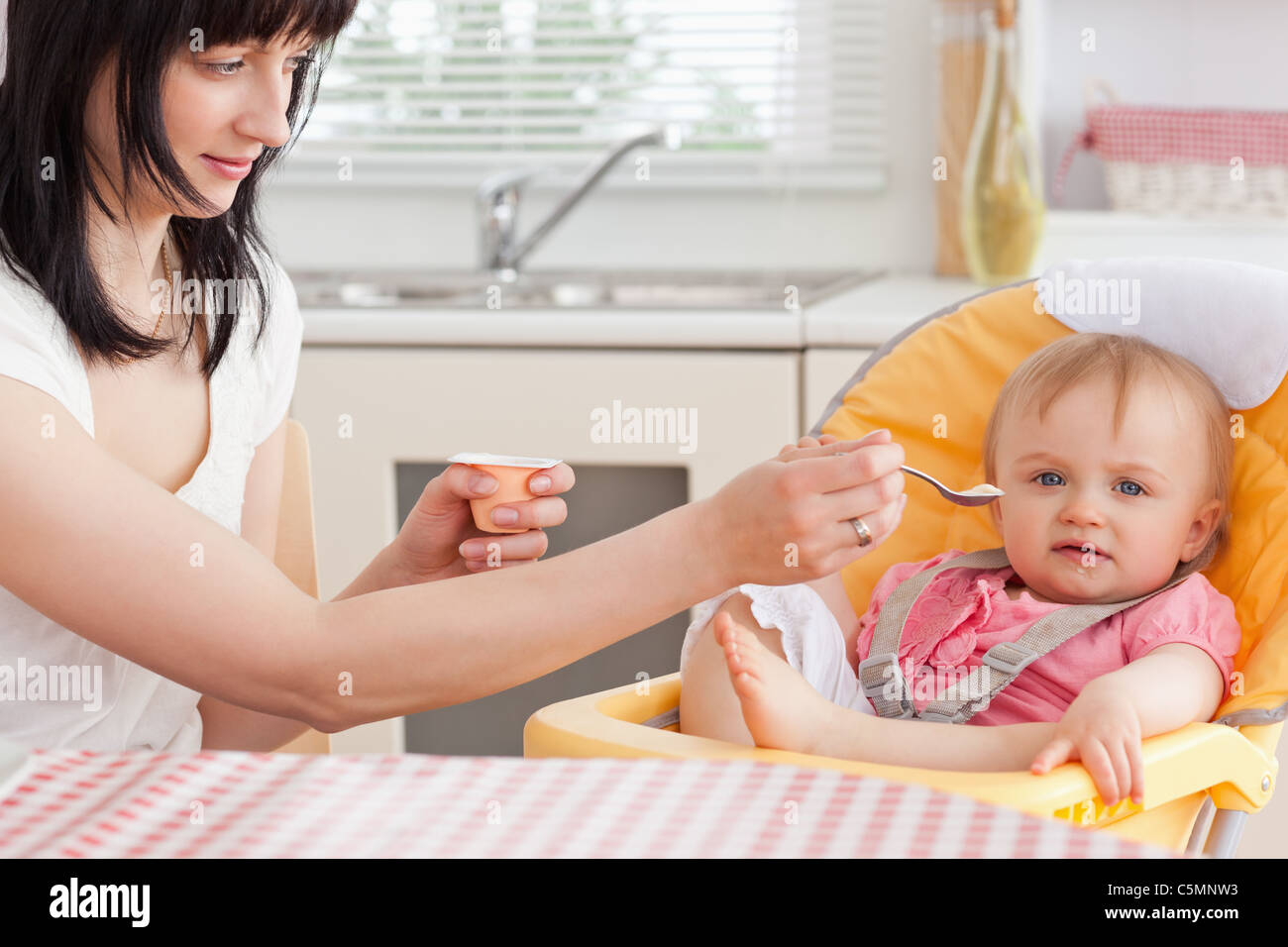 Attractive brunette woman feeding her baby while sitting Stock Photo ...