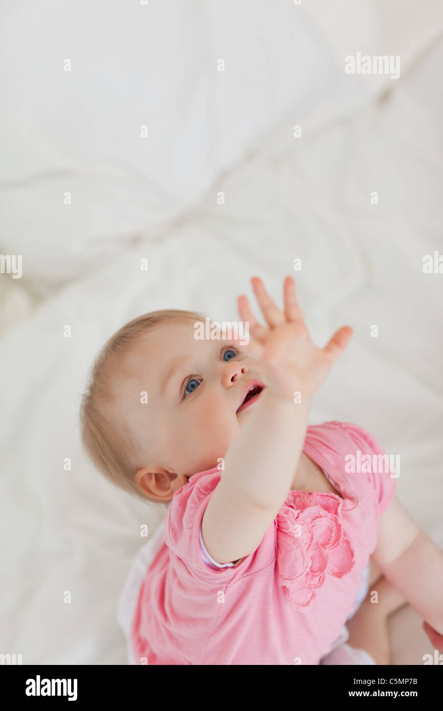 Cute baby wanting to catch something while sitting on a bed Stock Photo ...