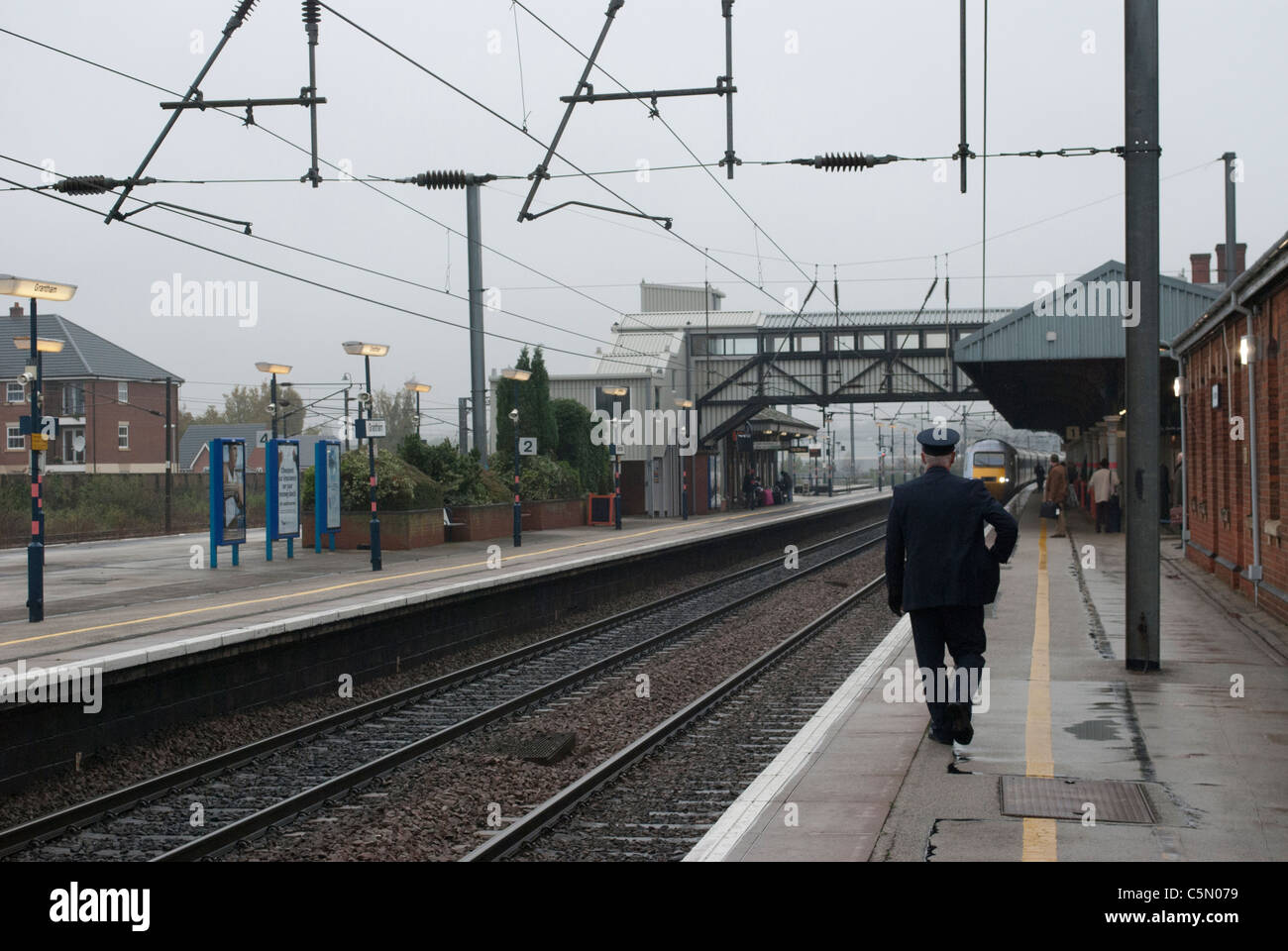 Guard walking along platform at Grantham station Stock Photo - Alamy