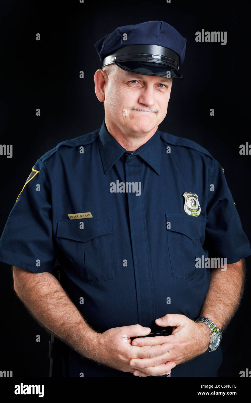 Portrait of a frustrated police officer, photographed against a black ...