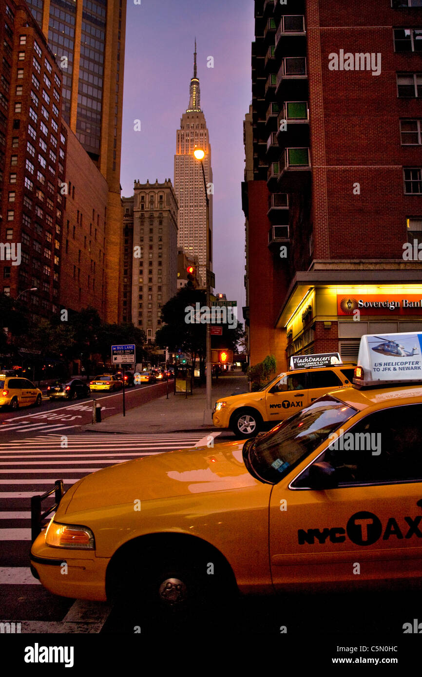 Street view with yellow taxi cabs towards empire state building at ...